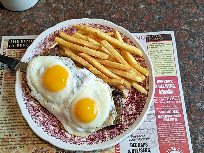 Two perfectly fried eggs with crispy edges and runny yolks alongside golden fries&mdash;proof that sometimes the simplest combinations deliver the most profound satisfaction.