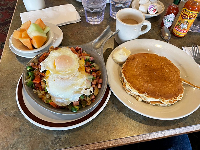 Breakfast nirvana achieved: a skillet packed with savory treasures crowned with perfectly cooked eggs, alongside pancakes that could double as pillows.