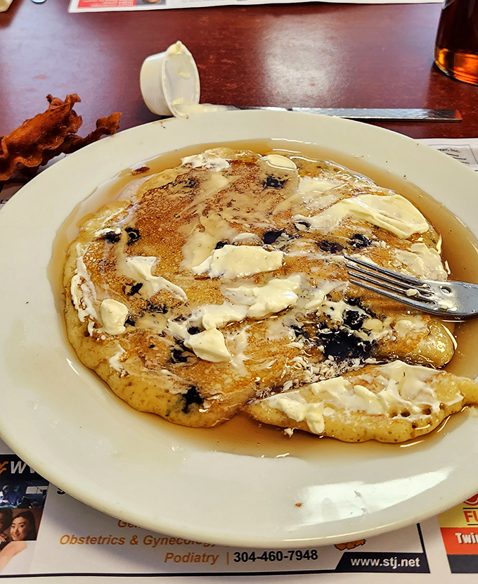 Melting butter creates golden pools on this blueberry masterpiece, proving that simplicity and quality trump pretension every time.