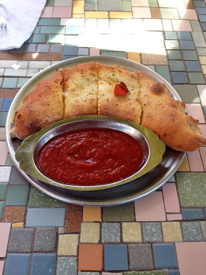 Not all heroes wear capes, but this calzone wears a perfect golden crust. That marinara dipping sauce deserves its own fan club.