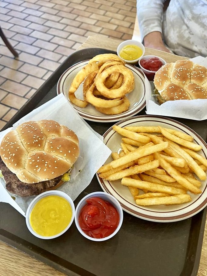 The holy trinity of comfort: golden onion rings, crispy fries, and burgers on paper&mdash;proof that sometimes the simplest pleasures are the most profound.