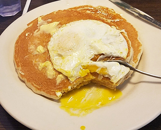 Breakfast architecture at its finest&mdash;a sunny-side-up egg crowning a pancake throne. The yolk breaks like sunrise over a carb horizon.