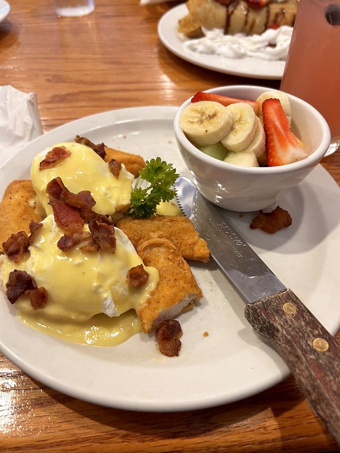 Behold the Benedict—poached eggs lounging on their throne, draped in hollandaise and accessorized with fresh fruit like royalty needs vitamins too.