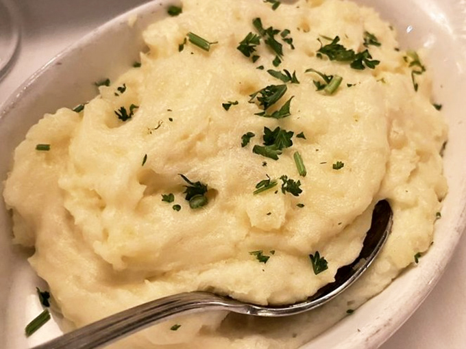 These mashed potatoes aren't just a side dish—they're the cloud-like cushion your steak deserves to rest beside, sprinkled with herbs like confetti at a celebration.