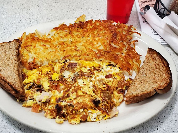 This isn't just an omelet &ndash; it's a masterclass in breakfast architecture with crispy hash browns standing guard like delicious sentinels.