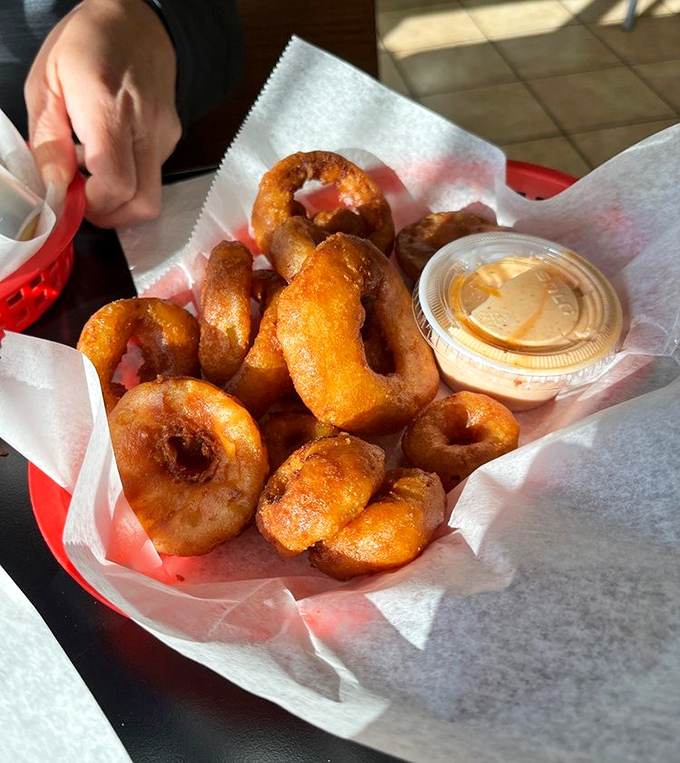 Golden-fried onion rings with that perfect crunch factor. The dipping sauce isn't just an accessory &ndash; it's an essential supporting character.