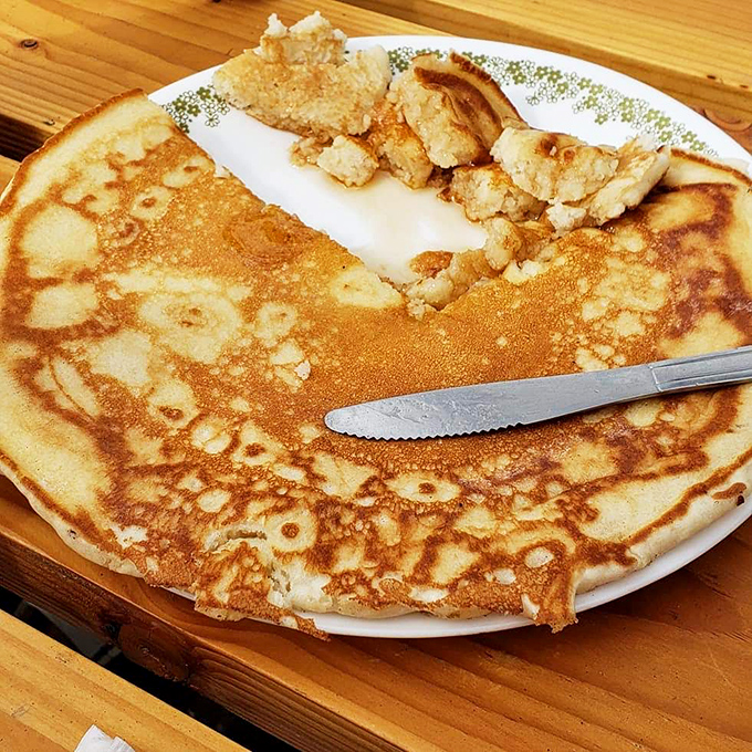This isn't just a pancake &ndash; it's a golden disc of joy that requires its own zip code. The knife suggests portion control, but who are we kidding?