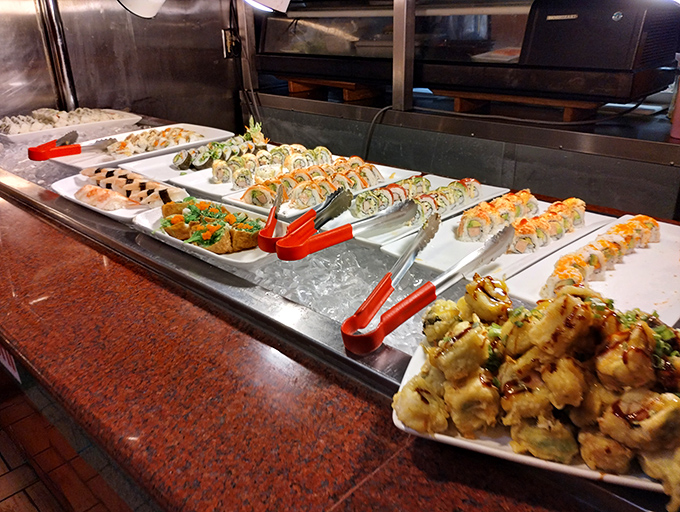 The sushi station stands ready for action, colorful rolls lined up like edible jewels. Buffet sushi: where quantity meets quality in surprising harmony.