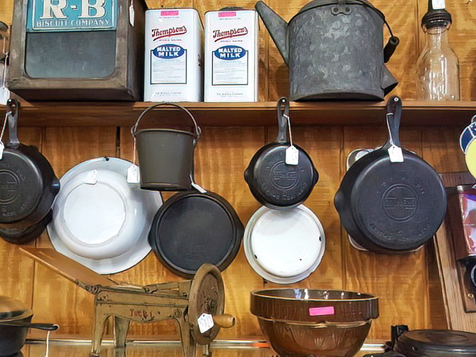Cast iron that's outlived generations of cooks, hanging like kitchen trophies. These pans have stories seasoned into them that no non-stick will ever tell.