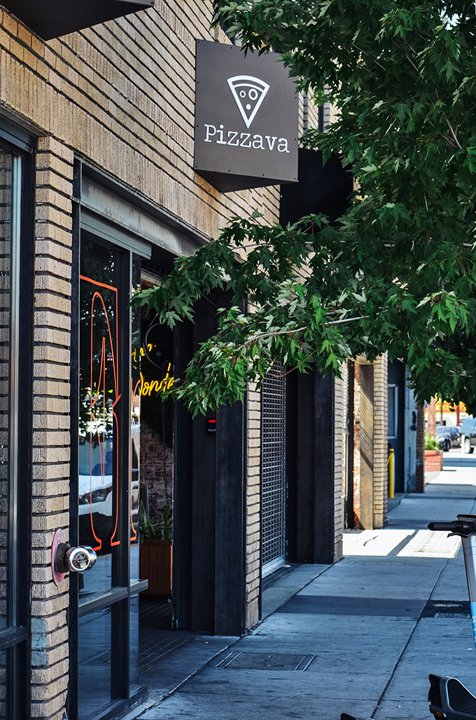 Pizzava's sleek black sign against tan brick&mdash;minimalist outside, maximalist flavors inside. 
