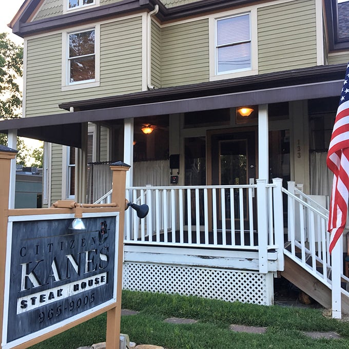 The white porch and American flag welcome you to Citizen Kane's &ndash; where steakhouse meets grandma's house in the best way.