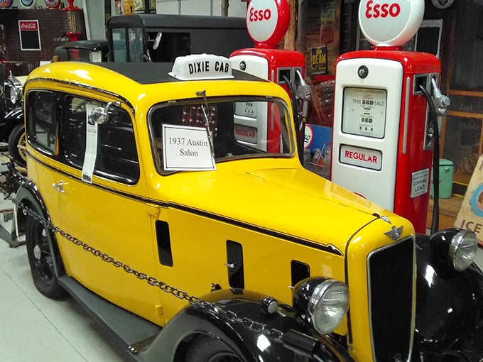 The sunshine-yellow 1937 Austin Salon pops against vintage Esso pumps, a cheerful reminder of when gas stations were service stations and attendants wore actual uniforms.