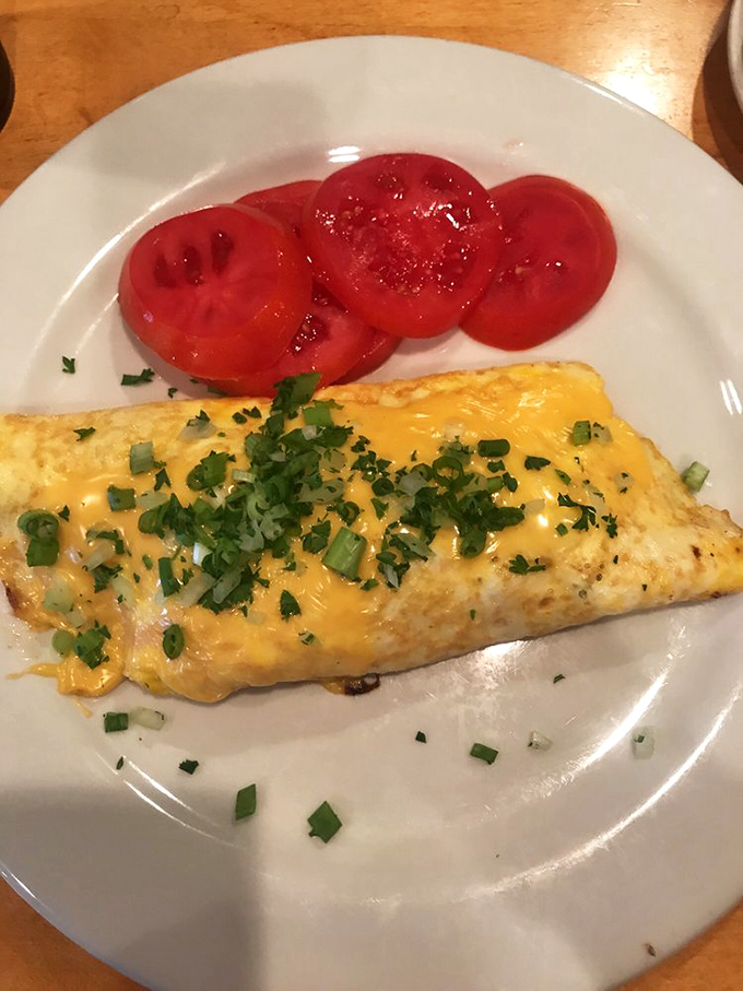 This isn't just an omelet&mdash;it's a cheese-draped sunrise on a plate, with tomatoes standing by like juicy red witnesses.