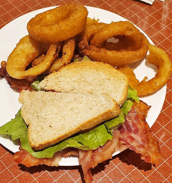A sandwich that understands priorities: more bacon than lettuce, paired with onion rings the size of bracelets. Diet starts tomorrow!