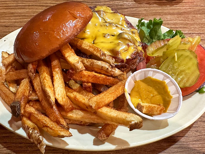 The bacon cheeseburger arrives like a beautiful sculpture that belongs in a museum, if museums celebrated the art of perfect comfort food.