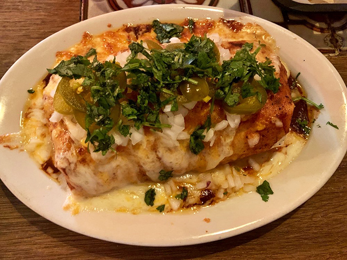 Melted cheese cascades over perfectly wrapped tortillas like a culinary waterfall, with jalape&ntilde;os standing guard over this flavor fortress.