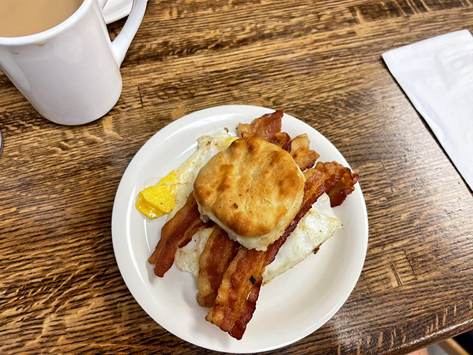 Breakfast architecture at its finest—a fluffy biscuit fortress protecting crispy bacon and eggs. The morning sandwich that's worth getting out of bed for.