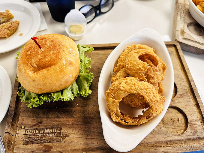 Perfectly toasted bread embraces a mountain of meat and cheese, while those golden onion rings stand ready for their moment of crispy glory.