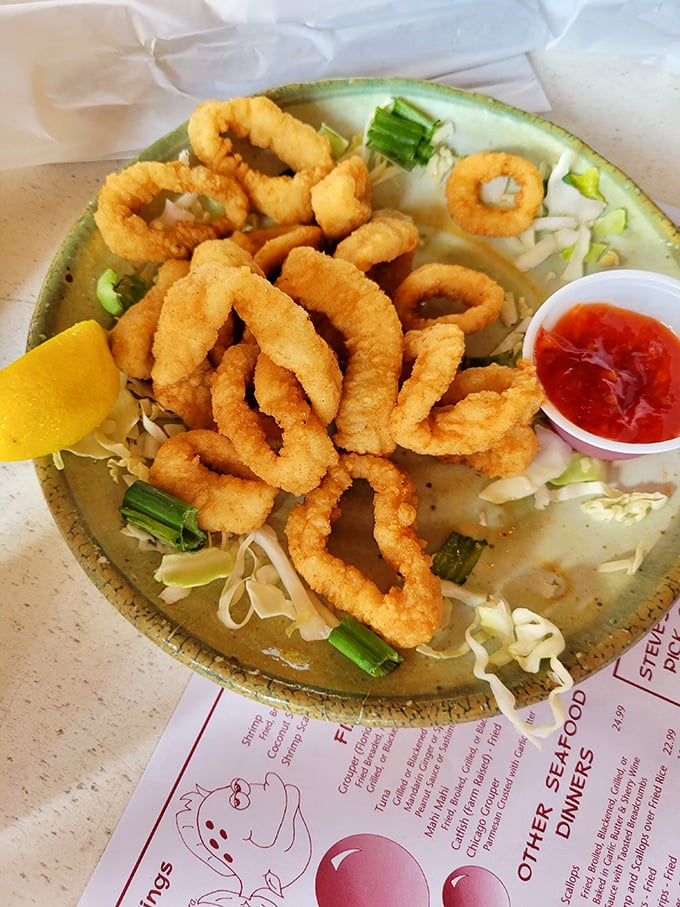 Perfectly crisp calamari rings perch atop shredded cabbage like golden halos, waiting for that satisfying dip into tangy cocktail sauce.