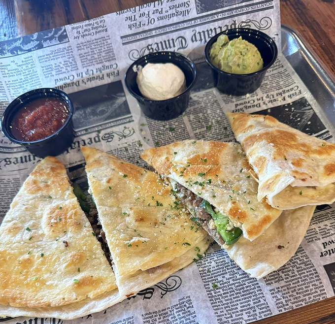 Perfectly grilled tortilla triangles revealing their cheese-pulled secrets, served on newspaper because good food stories deserve to make headlines.