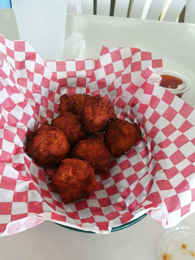 Golden hushpuppies nestled in checkered paper&mdash;little orbs of cornmeal joy that make you wonder why you don't eat these every single day.