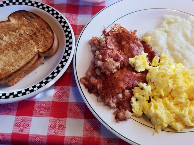 Breakfast alchemy at its finest: eggs, corned beef hash, and potatoes sharing a plate like old friends at a reunion. The grits aren't just a side—they're a statement.