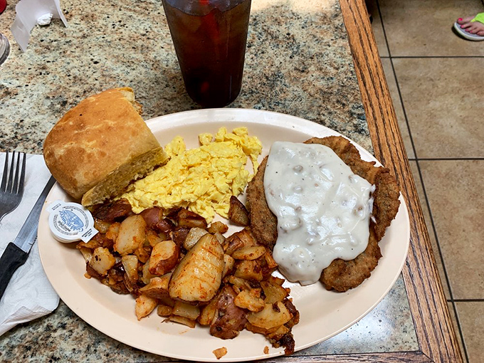 Country fried steak done right – crispy exterior, tender inside, smothered in gravy that could make cardboard taste good, with eggs and potatoes playing perfect backup.