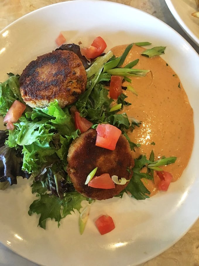 Behold the legendary crab cakes that inspire road trips &ndash; golden beauties nestled on greens like edible treasure chests.