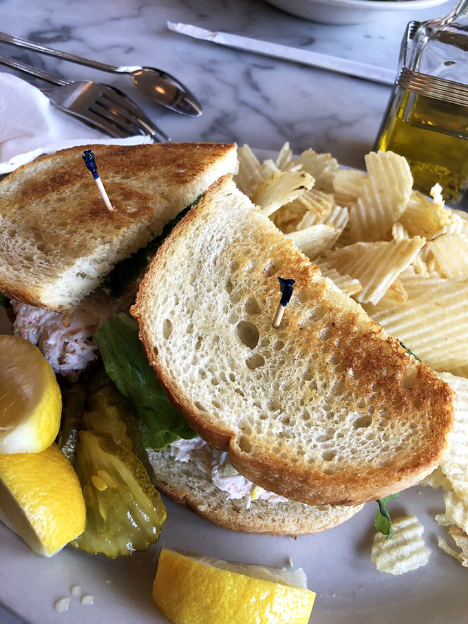 Golden-toasted bread embracing a generous filling, with house-made chips standing by like loyal companions.