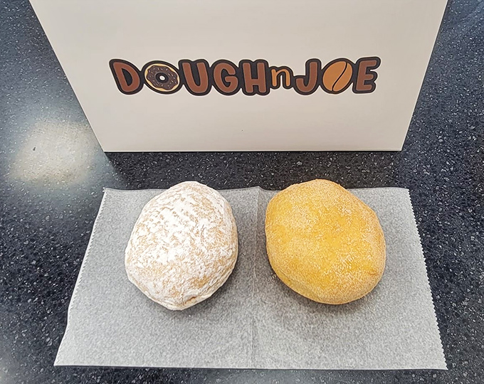 Two perfect spheres of joy—one powdered, one glazed—sitting like edible zen stones, reminding us that simplicity often delivers the most profound pleasure.