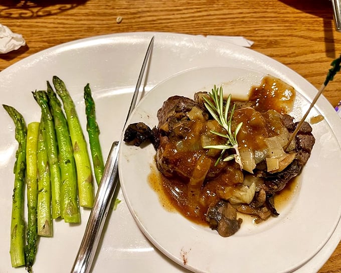 A filet mignon bathed in rich sauce, standing tall like a meaty monument to culinary excellence. Those asparagus spears aren't just garnish&mdash;they're witnesses to greatness.