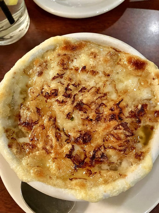 This French onion soup isn't just topped with cheese; it's wearing a molten crown of bubbly, bronzed perfection.