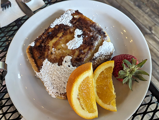 French toast dusted with powdered sugar, flanked by fresh fruit&mdash;breakfast that straddles the line between meal and dessert with delicious defiance.