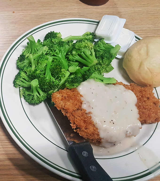 Comfort food perfection: a golden-fried steak smothered in creamy gravy alongside vibrant broccoli. Simple pleasures done absolutely right.