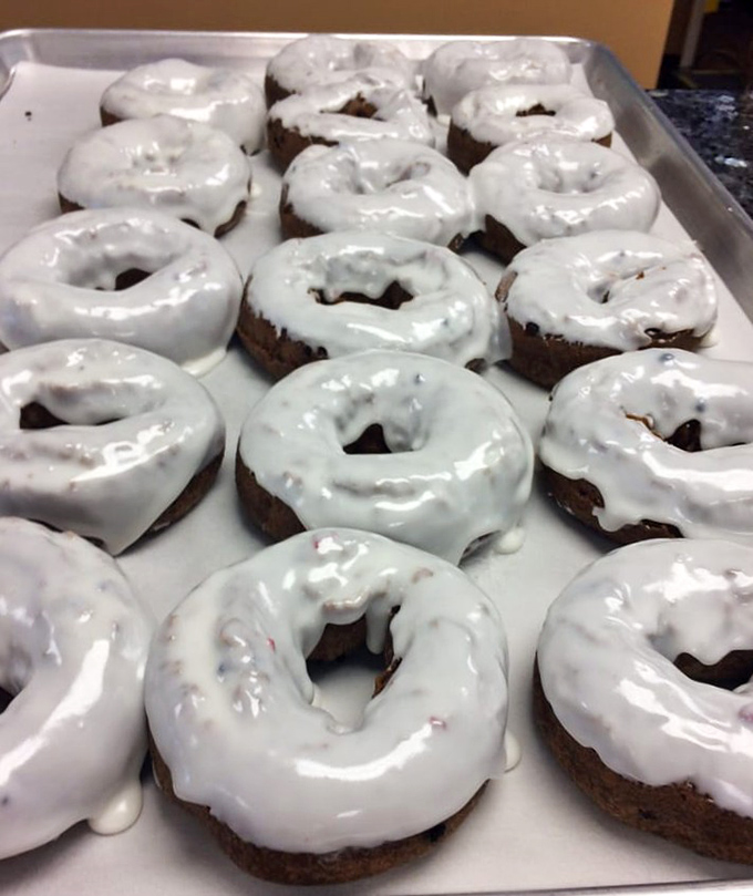 A tray of glazed chocolate cake donuts awaiting their destiny. Like well-dressed guests at a party, they're too pretty to ignore.