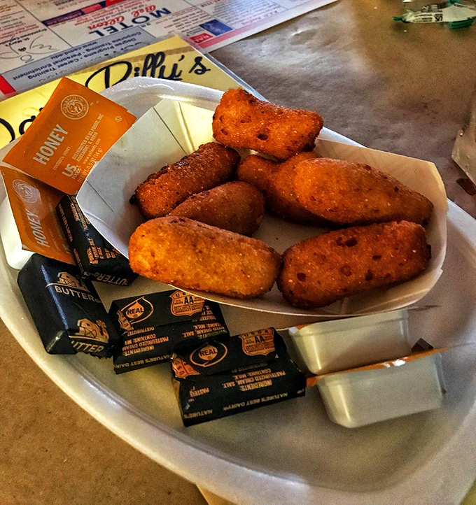 Hush puppies so perfectly golden they deserve their own trophy, served with enough butter packets to make your cardiologist wince.