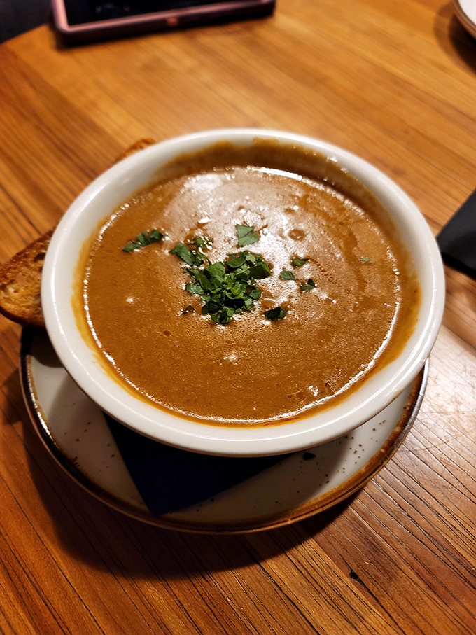 A velvety bisque that whispers of slow-simmered goodness, garnished with fresh herbs that brighten each spoonful.