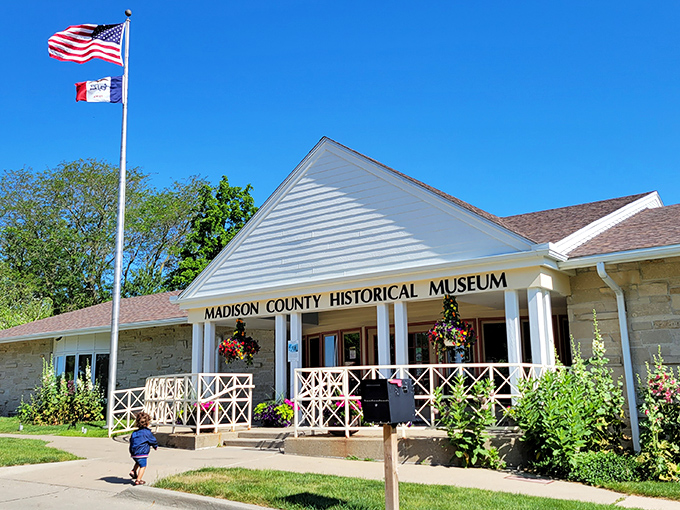 The Madison County Historical Museum welcomes visitors with classic white columns and flowering gardens, a gateway to stories that shaped this corner of Iowa.