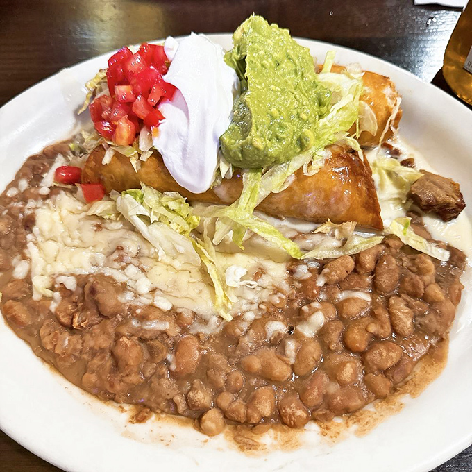 A fiesta on a plate! Rice, beans, and a crispy chimichanga topped with all the fixings create a symphony of textures that'll have your taste buds dancing the jarabe tapat&iacute;o.