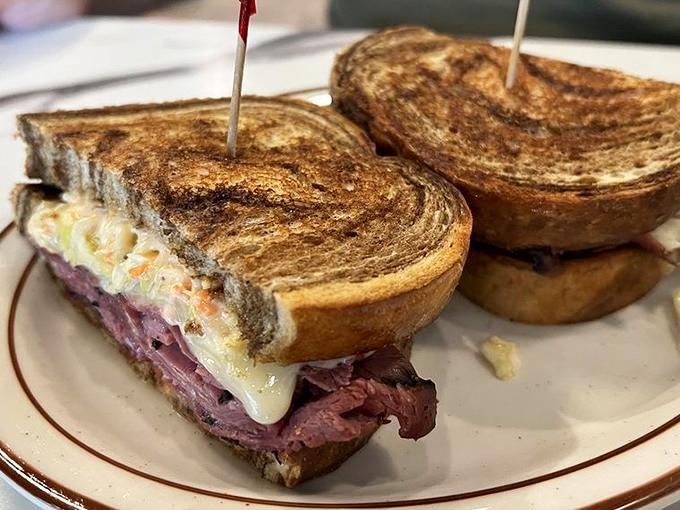 Pastrami stacked so perfectly it could teach architecture classes. The melted cheese cascades like a dairy waterfall of dreams.