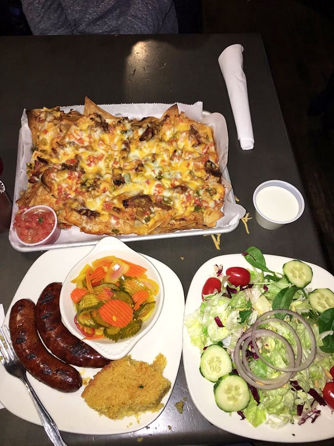 A mountain of loaded nachos that requires a climbing strategy, with sausage and pickles standing guard at base camp.