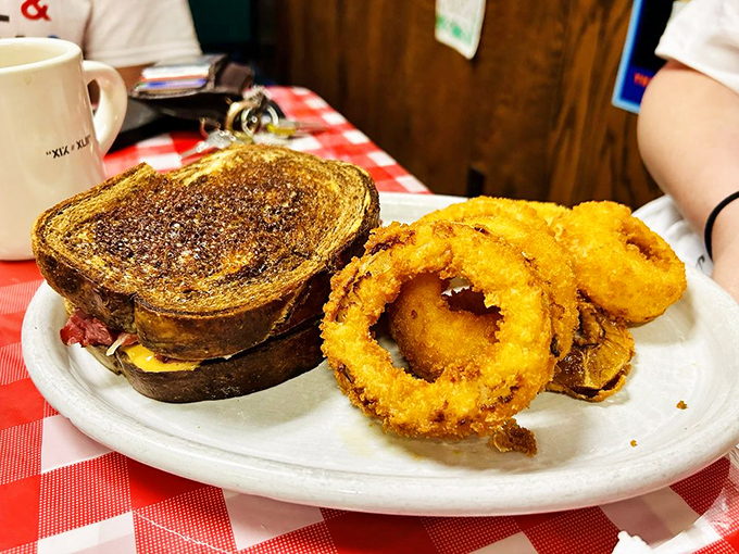 Golden-brown onion rings stand guard beside a sandwich that's achieved the perfect balance of crispy exterior and melty interior&mdash;the diner sandwich hall of fame awaits.