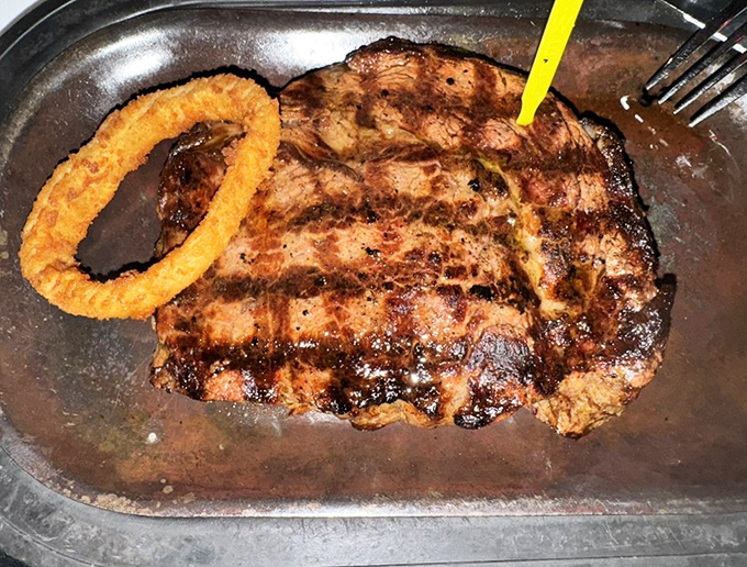 A ribeye with perfect grill marks and an onion ring companion&mdash;like Batman and Robin, if they were delicious and made you happier than any superhero.