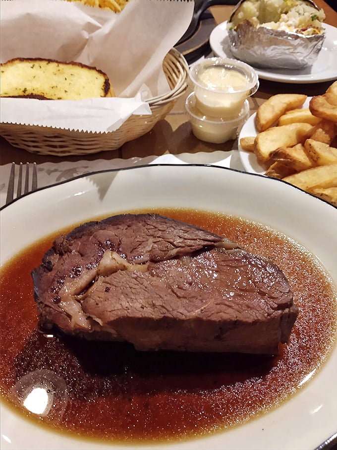Prime rib swimming in its natural habitat of savory au jus, flanked by golden steak fries and buttery bread. The holy trinity of comfort.