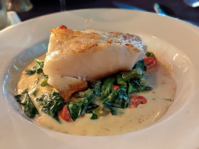 The legendary Chilean Sea Bass sits like royalty atop a throne of spinach, its golden crust hiding the buttery treasure beneath.