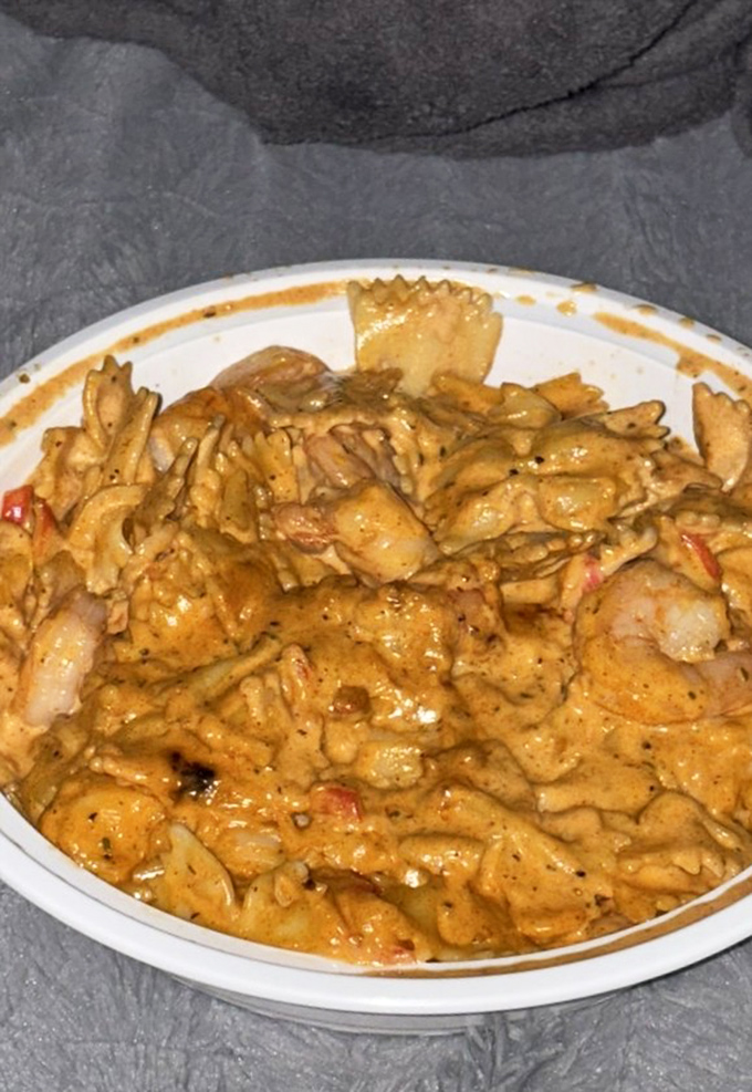 The seafood pasta's rich, amber-hued sauce clings lovingly to each farfalle fold, creating the perfect delivery system for Cajun flavor bombs. 