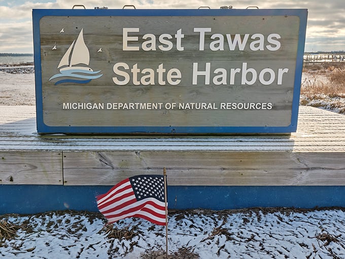 Winter transforms East Tawas State Harbor into a serene wonderland. The snow-dusted sign stands as a frosty invitation to discover Lake Huron's quieter, contemplative season.