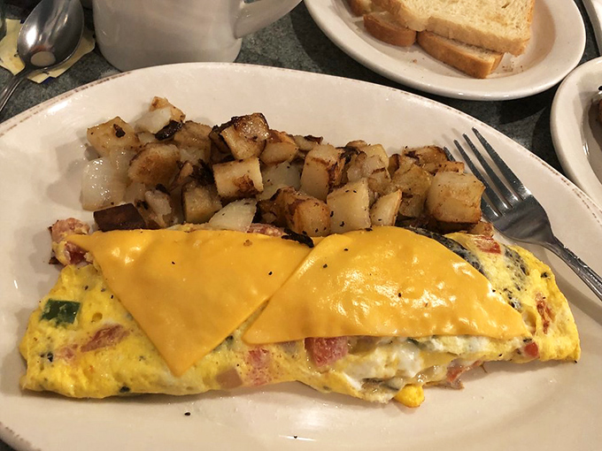 This isn't just any omelet&mdash;it's a golden envelope delivering a message of cheesy, savory goodness alongside home fries crisped to perfection.