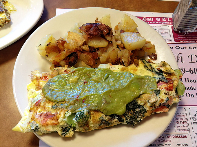 Green goddess meets morning masterpiece&mdash;this veggie omelet wears its avocado crown proudly while potatoes huddle nearby, crisped to golden perfection. 