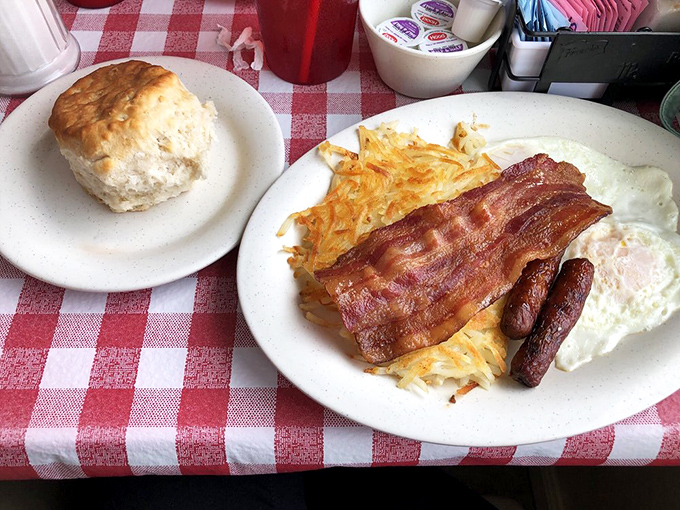 The classic American breakfast trinity: perfectly cooked eggs, crispy hash browns, and a biscuit standing sentry like it knows its importance.